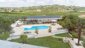 Área da piscina com espreguiçadeiras, um espaço coberto para relaxar e vista do horizonte.