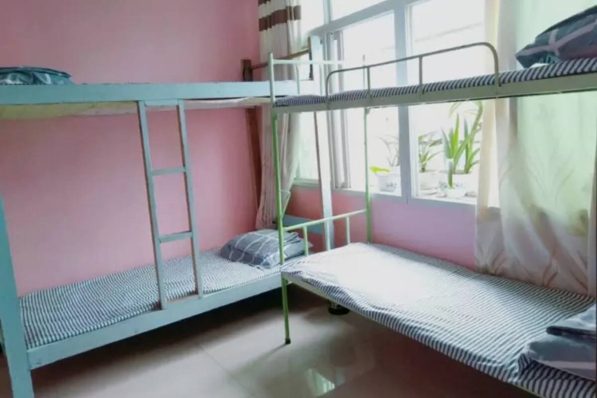 Quarto com beliche, janela e uma pequena mesa.