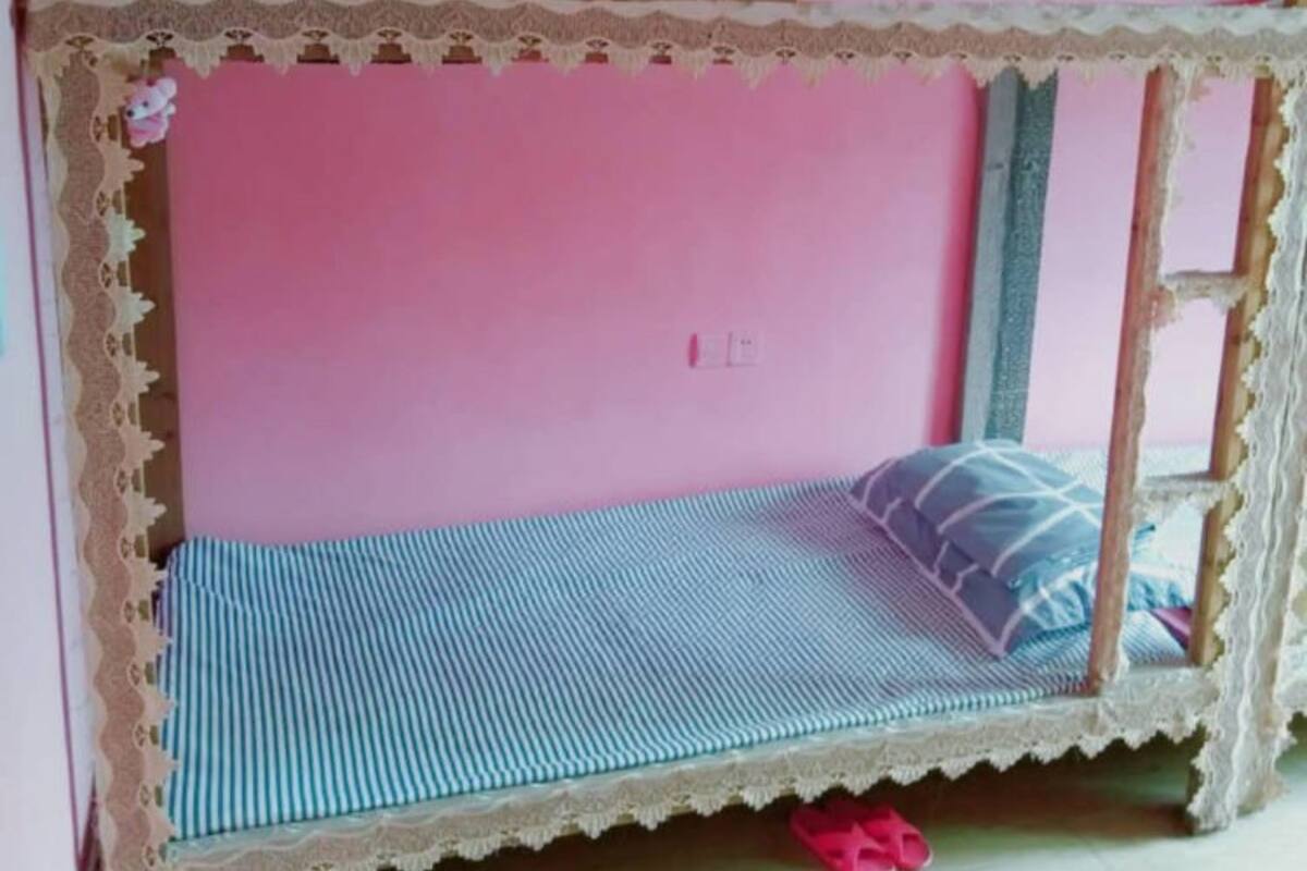 Uma cama de solteiro com estrutura de madeira e acabamento em renda.