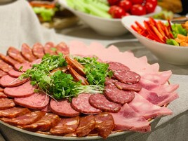 Um prato com fatias de carne e vegetais frescos.