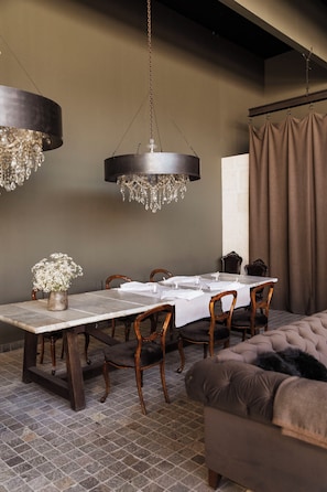 Uma sala de jantar com mesa de mármore, cadeiras de madeira e um candelabro.