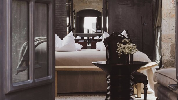 Um quarto com uma cama, uma mesa com um vaso e um candelabro.