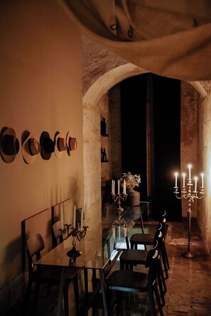 Uma sala de jantar com pouca luz, com uma mesa comprida, cadeiras e um candelabro.