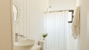 Casa de banho com uma sanita branca, lavatório e cortina de chuveiro.