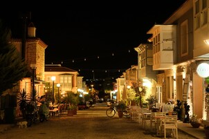 Rua com edifícios, mesas ao ar livre e luzes de Natal.