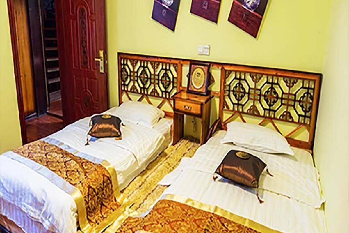 Quarto duplo com duas camas, cada uma com cabeceira, mesa de cabeceira e criado-mudo.