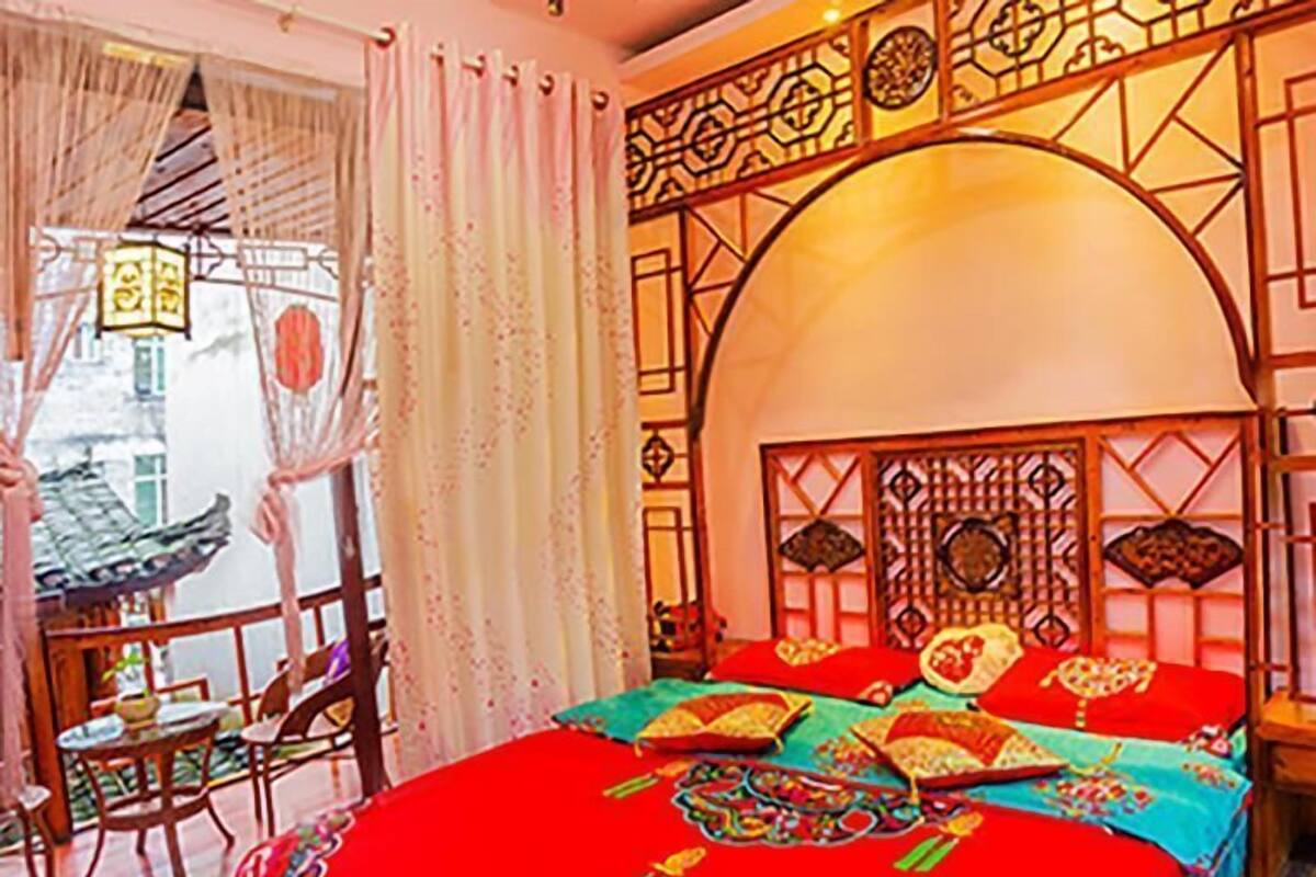 Quarto tradicional com cama, cortinas, mesa e cadeiras.