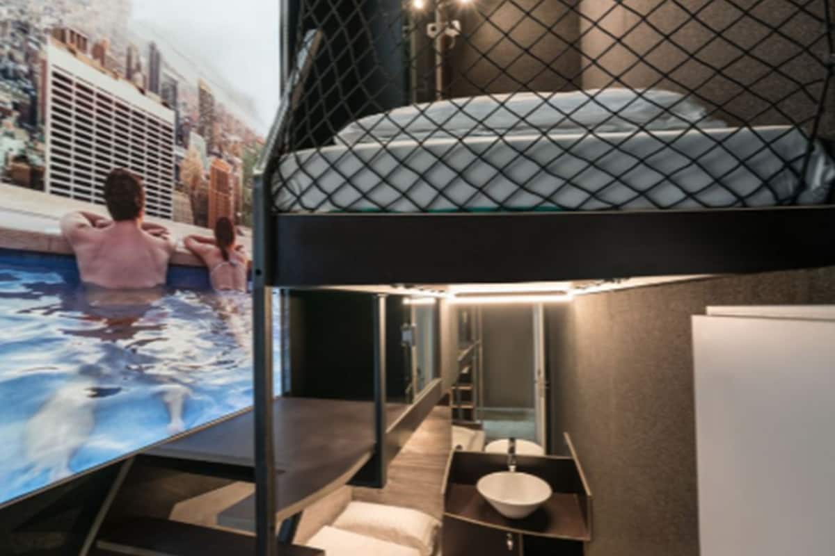 Quarto de hotel moderno com beliche, ampla janela com vista para a cidade, área de piscina privativa e banheiro minimalista.