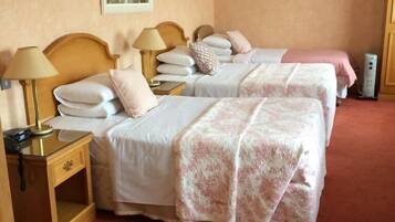 Quarto de hotel com duas camas, uma mesa de cabeceira com abajur, um quadro na parede e um aparelho de ar condicionado.