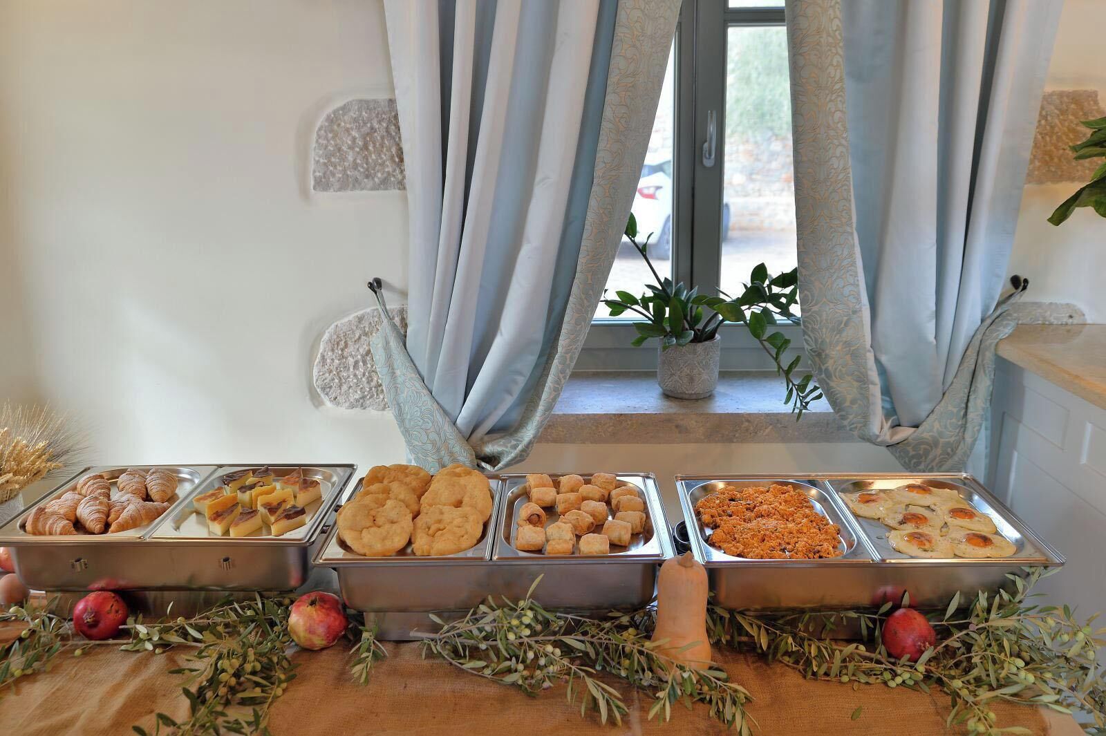 Mesa de buffet com diversos alimentos e uma romã sobre uma toalha.