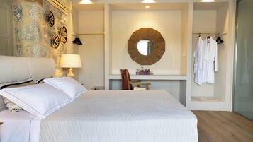 Quarto com cama grande, parede de pedra, espelho, penteadeira e porta-robes.