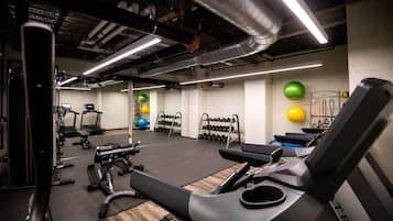 Ginásio com esteiras, máquinas de peso e bolas de exercício.