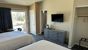 Quarto de hotel com duas camas, televisão, cômoda, cafeteira e vista para o exterior.