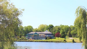Um edifício à beira do lago, com um cais, cercado por vegetação exuberante e árvores.