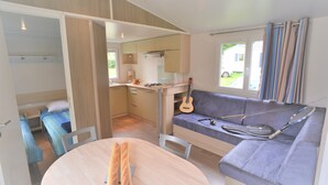 Um espaço compacto com cozinha compacta, área de refeições com mesa e cadeiras, um sofá e uma guitarra.