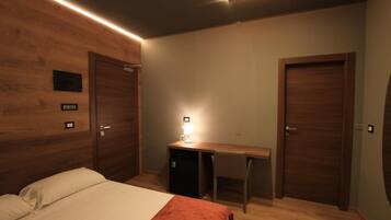 Quarto com cama, escrivaninha e duas portas.