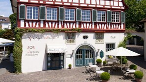 Um edifício tradicional de enxaimel com um café chamado "Bäckerei Café" e uma placa para "Gasthaus Löven".