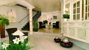 Um hall amplo com escada, assentos confortáveis e plantas decorativas.