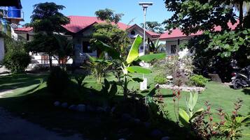 Zona residencial com casas, um poste de luz solar e um jardim bem cuidado com diversas plantas e gramado.