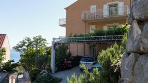Um prédio residencial com varanda, um carro estacionado e uma scooter.
