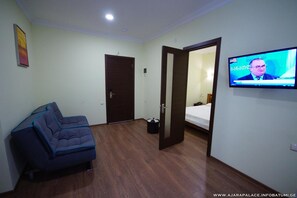 Quarto de hotel com sofá, televisão e cama.