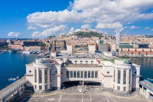 Um edifício à beira-mar com uma grande entrada central, várias janelas e um corpo de água ao redor.