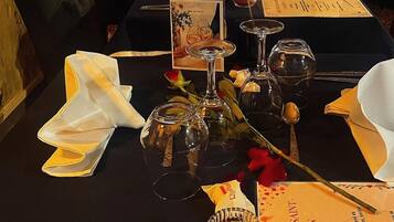 Mesa posta para refeição, com cardápio, copos de vinho e uma vela.