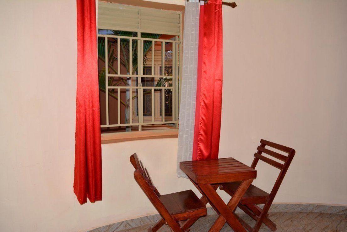 Um quarto com janela, uma mesa e duas cadeiras.