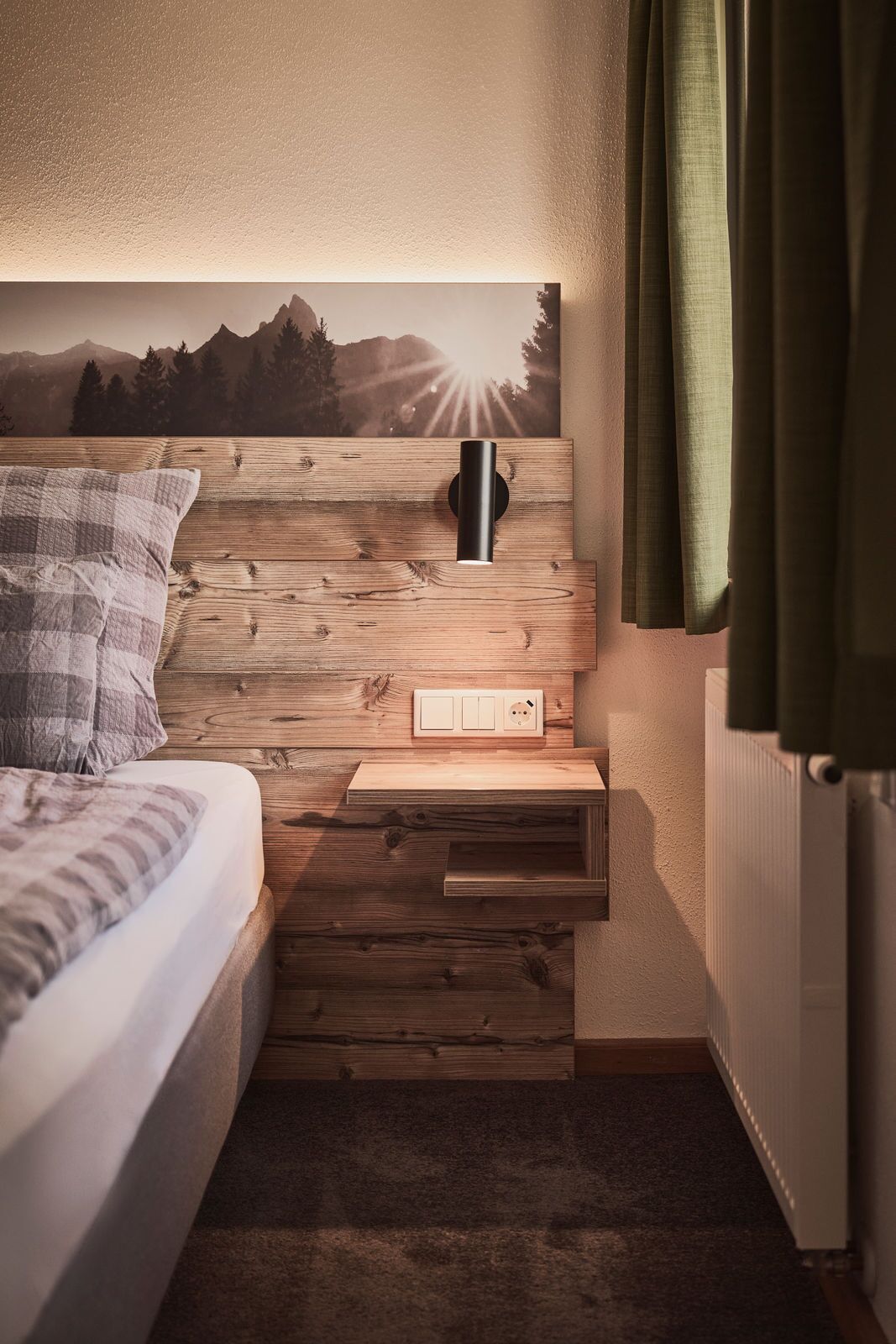 Quarto com cabeceira de madeira, mesa de cabeceira com abajur e tomada na parede.