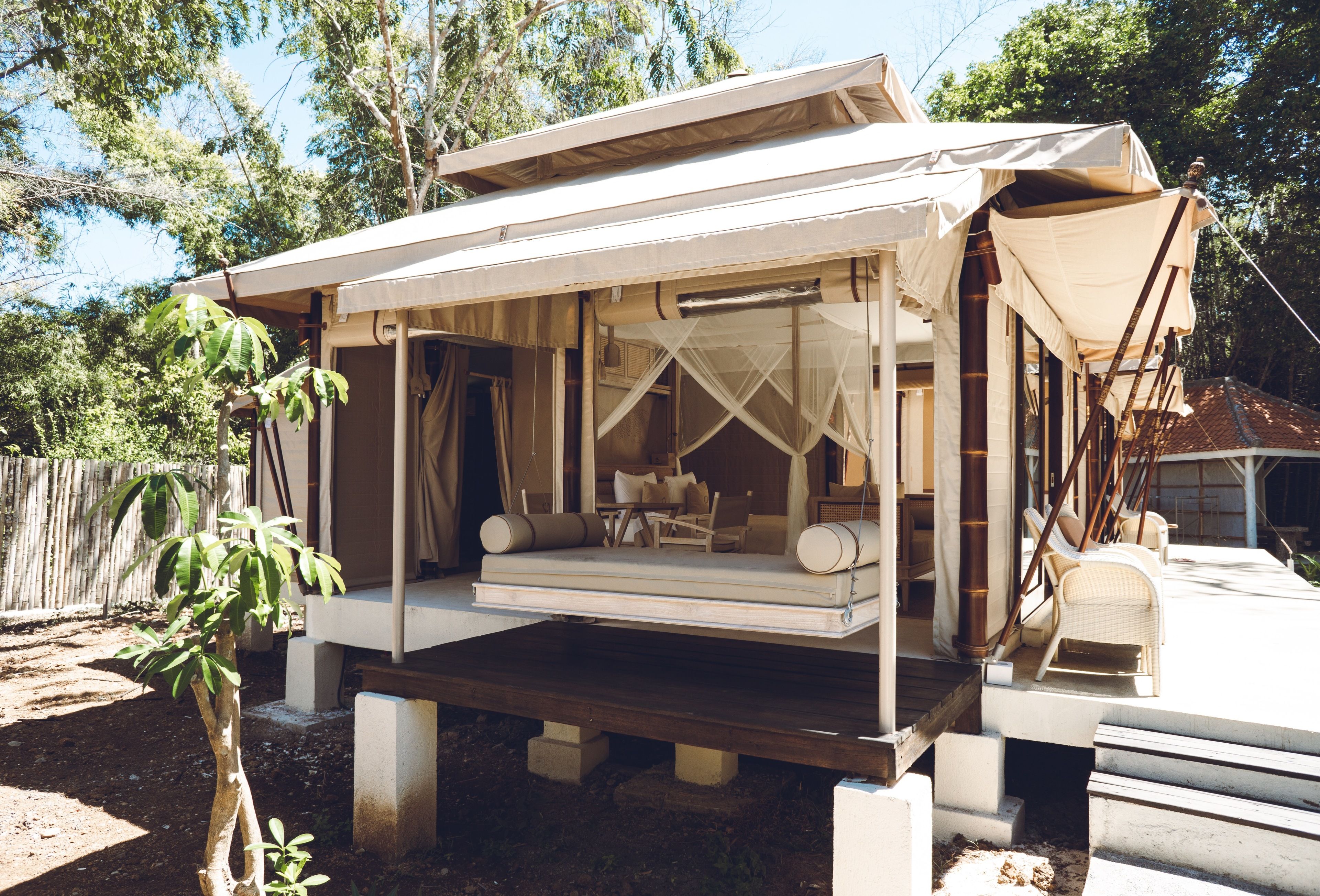 Uma tenda espaçosa com plataforma elevada, oferecendo área de dormir ao ar livre e um toldo.