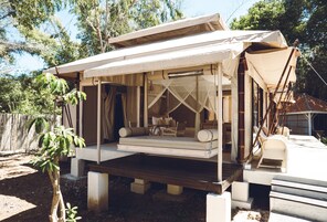 Uma tenda espaçosa com plataforma elevada, oferecendo área de dormir ao ar livre e um toldo.