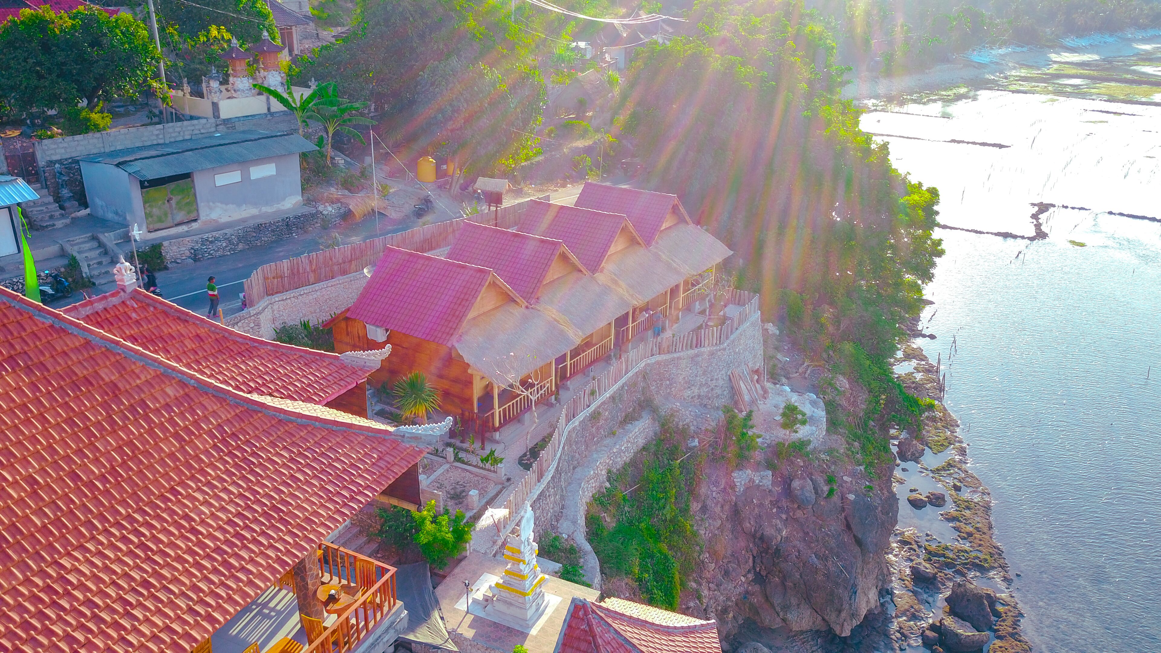 Um edifício tradicional com telhados de terracota vermelha, um caminho de pedra e vista para um corpo de água.