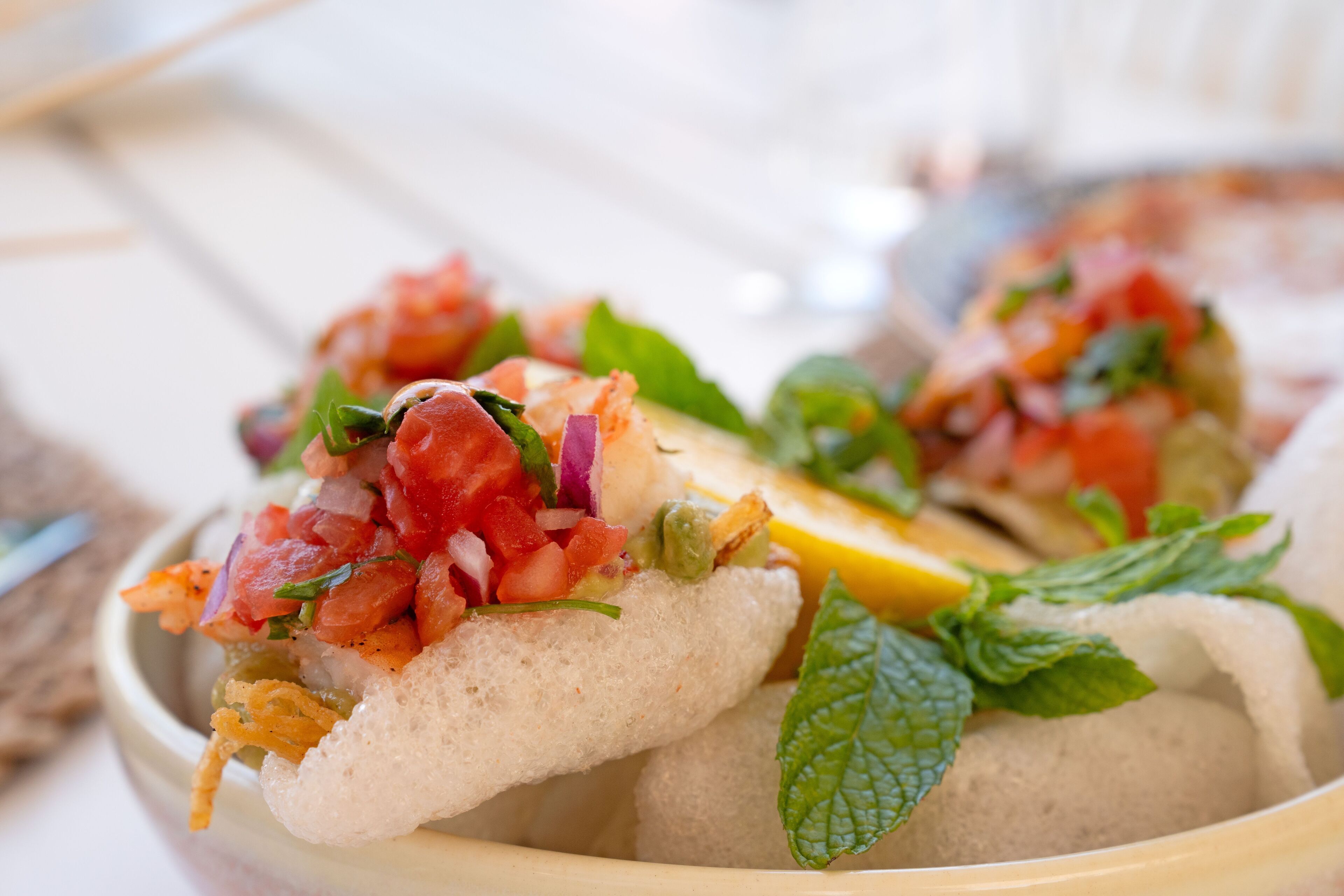 Uma tigela de bruschetta coberta com tomate, cebola e ervas picados, decorada com folhas de hortelã.