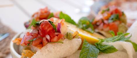 Uma tigela de bruschetta coberta com tomate, cebola e ervas picados, decorada com folhas de hortelã.
