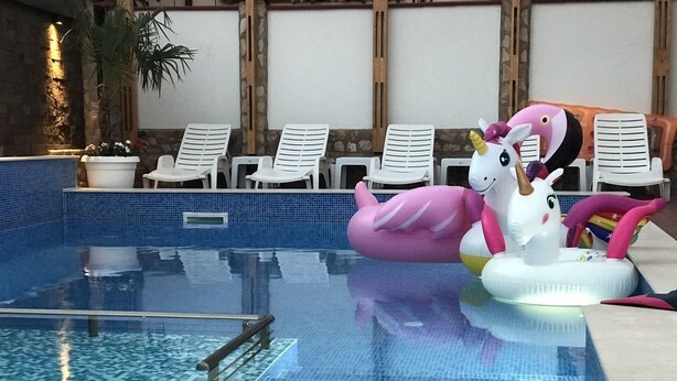 Uma piscina com espreguiçadeiras e boias de unicórnio.
