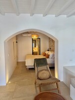 Quarto moderno com cama, cadeira e espelho.