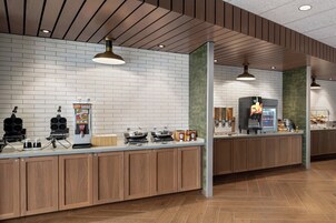 Cozinha moderna com parede de tijolos, armários de madeira e máquina de café.