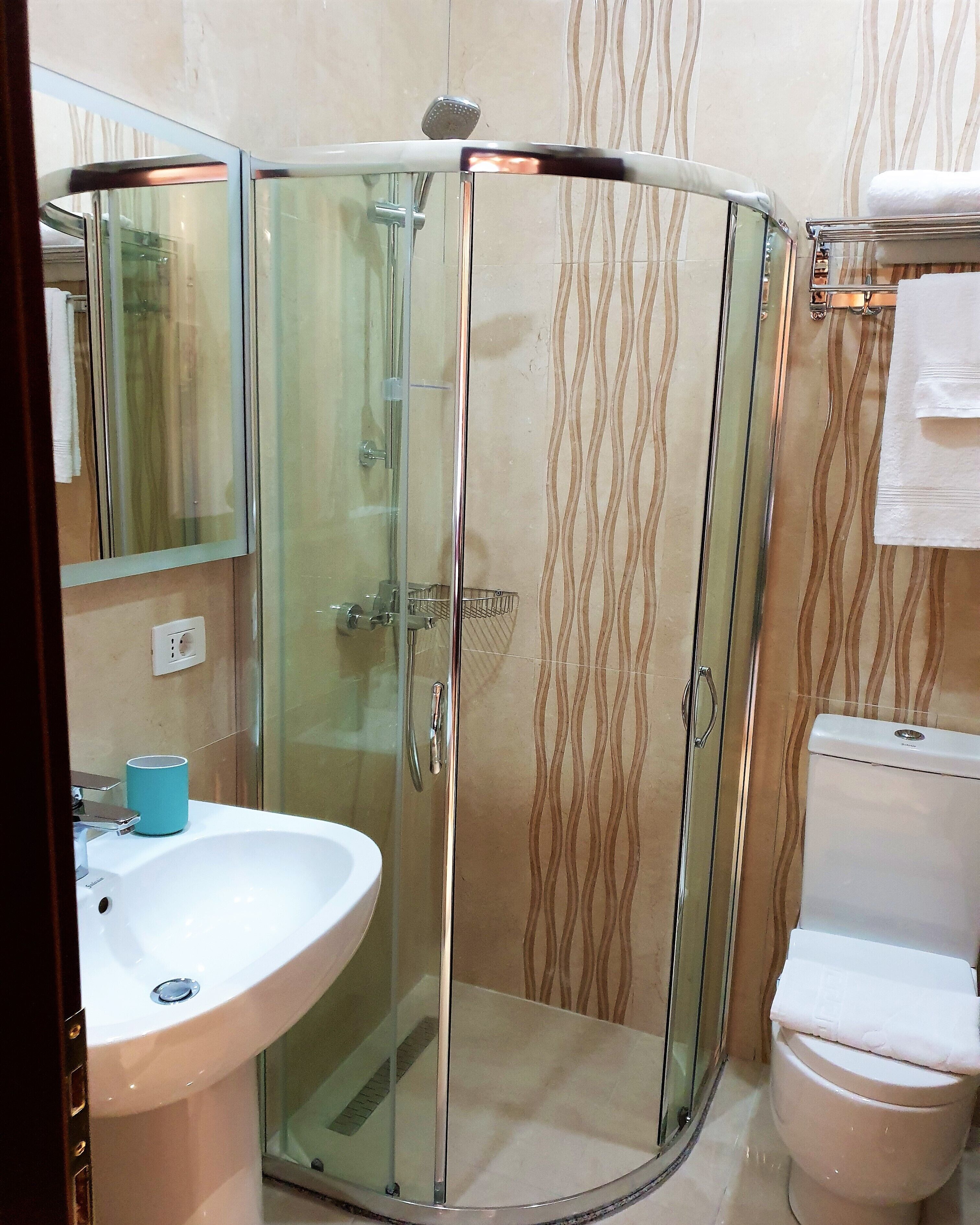 Uma casa de banho moderna com chuveiro em cabine de vidro, lavatório branco e sanita.