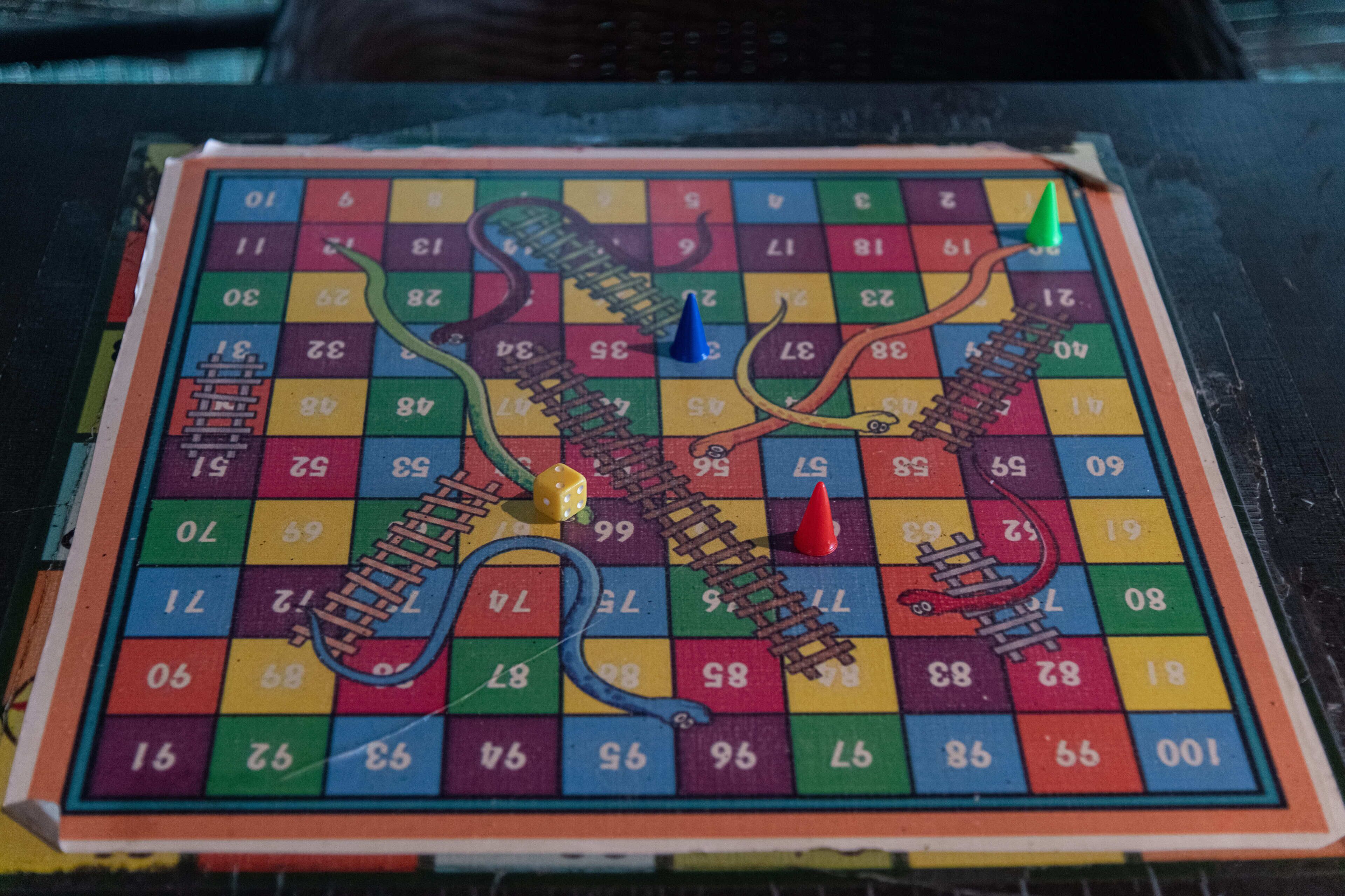 Um jogo de tabuleiro com uma grade colorida e casas numeradas.