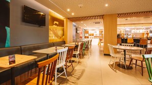 Interior de restaurante com cabines, mesas e área de cozinha.