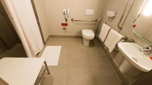 Casa de banho pequena e limpa, com sanita, lavatório e zona de duche.