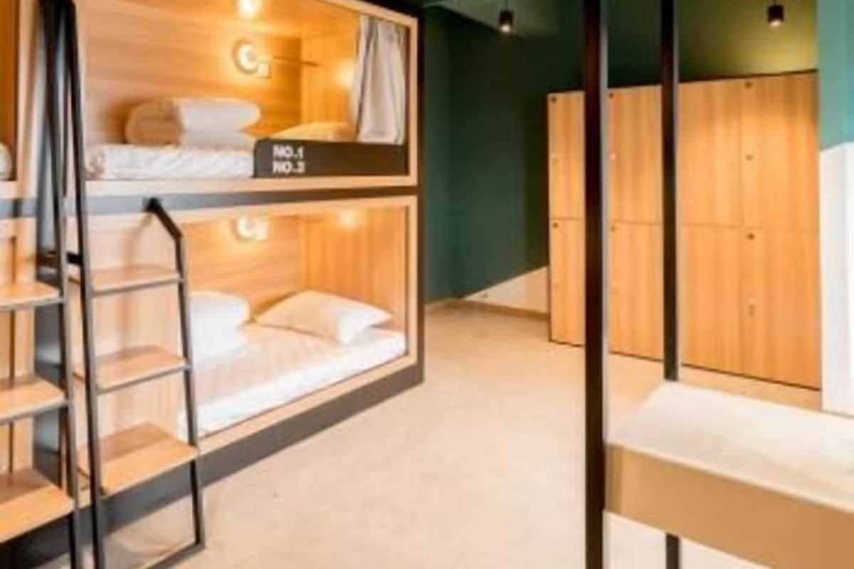 Quarto de hotel com beliches, uma escrivaninha e um guarda-roupa.