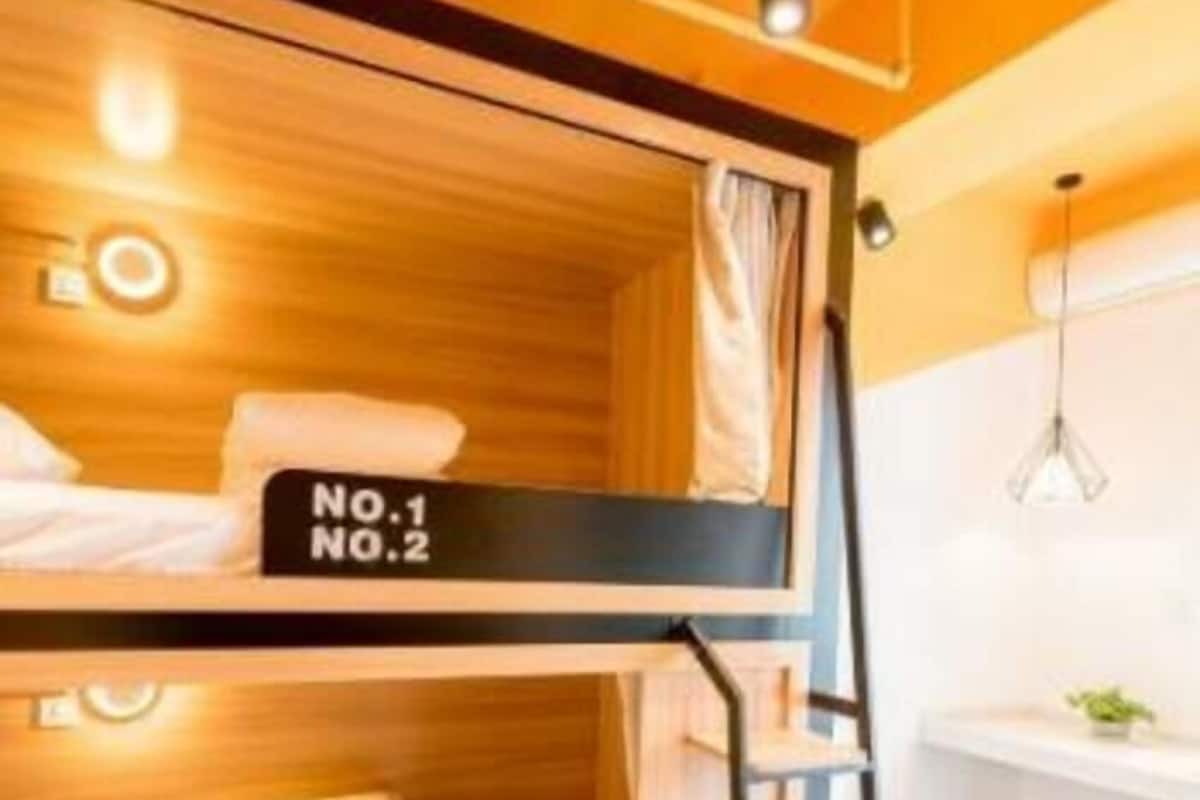 Quarto com beliche, uma mesa pequena e luminária pendente.