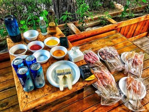 Uma mesa de madeira com comida, temperos e bebidas.