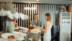 Disposição de buffet com vários pratos e uma planta decorativa.