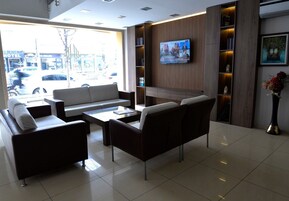 Um hall de hotel moderno com sofá, poltronas, mesa de centro e televisão na parede.