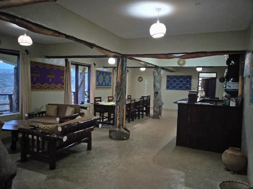 Interior rústico com sofá de madeira, mesas de jantar e cozinha.