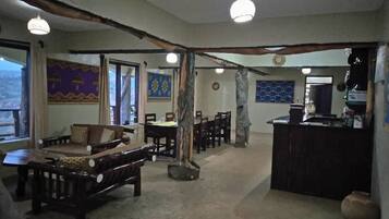 Interior rústico com sofá de madeira, mesas de jantar e cozinha.