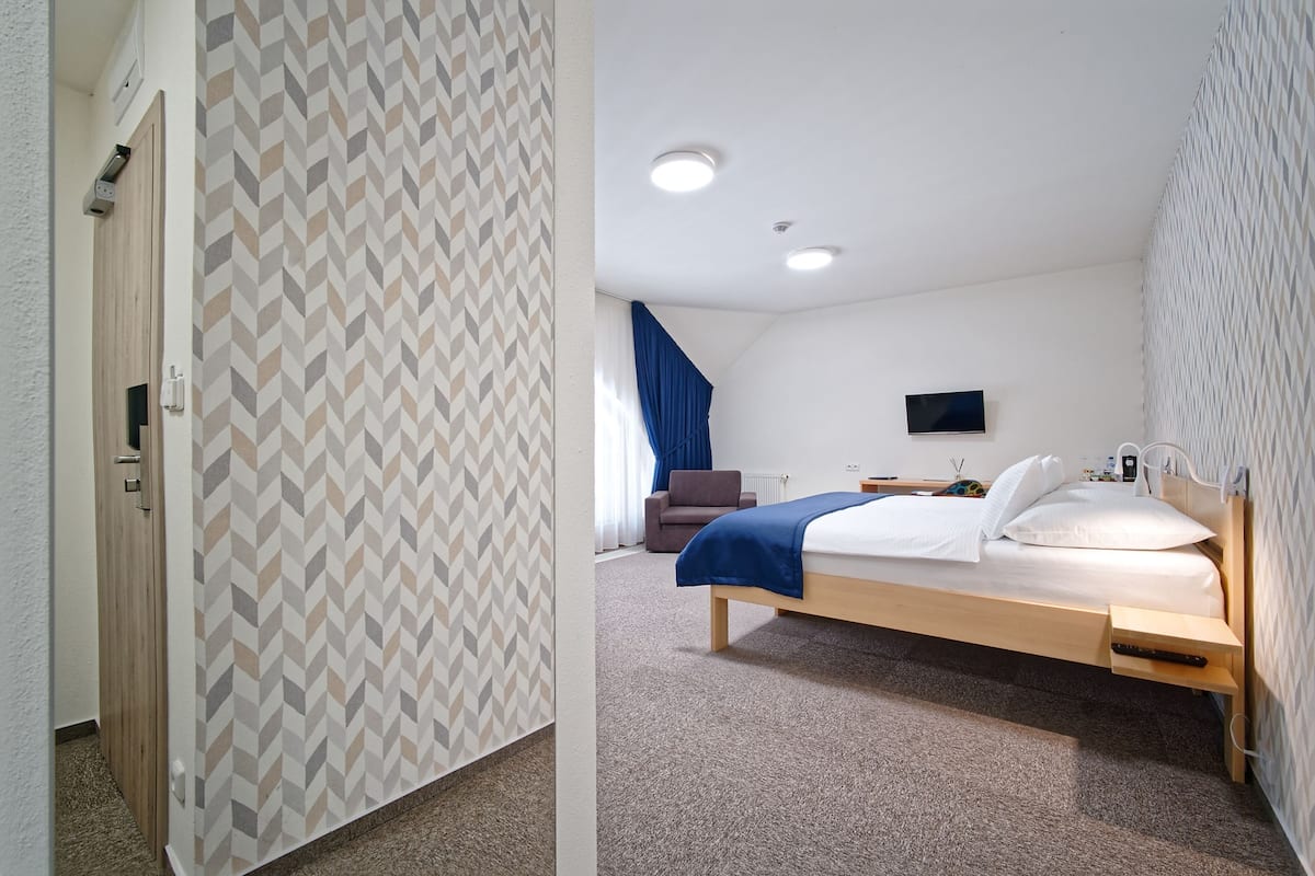 Quarto com cama, cadeira, televisão e escrivaninha.