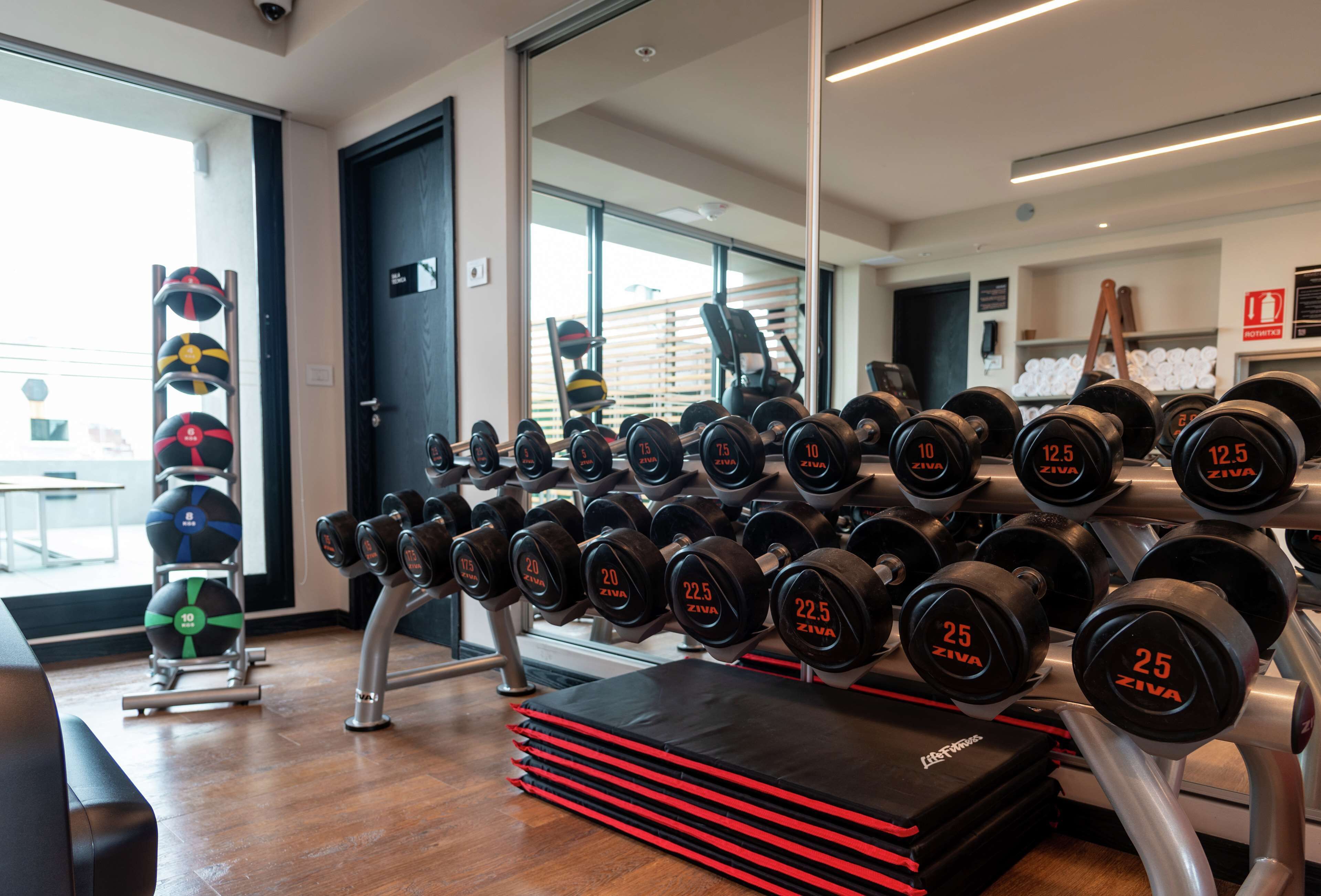 Uma academia com diversos equipamentos de musculação, incluindo halteres e um banco.